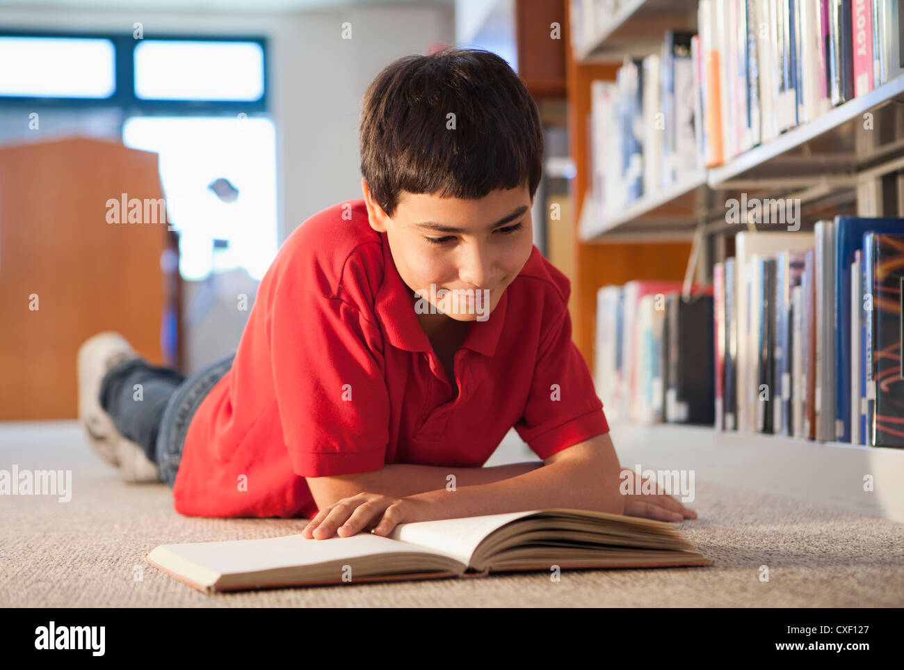 Hispanic boy reading book in library Stock Photo - Alamy