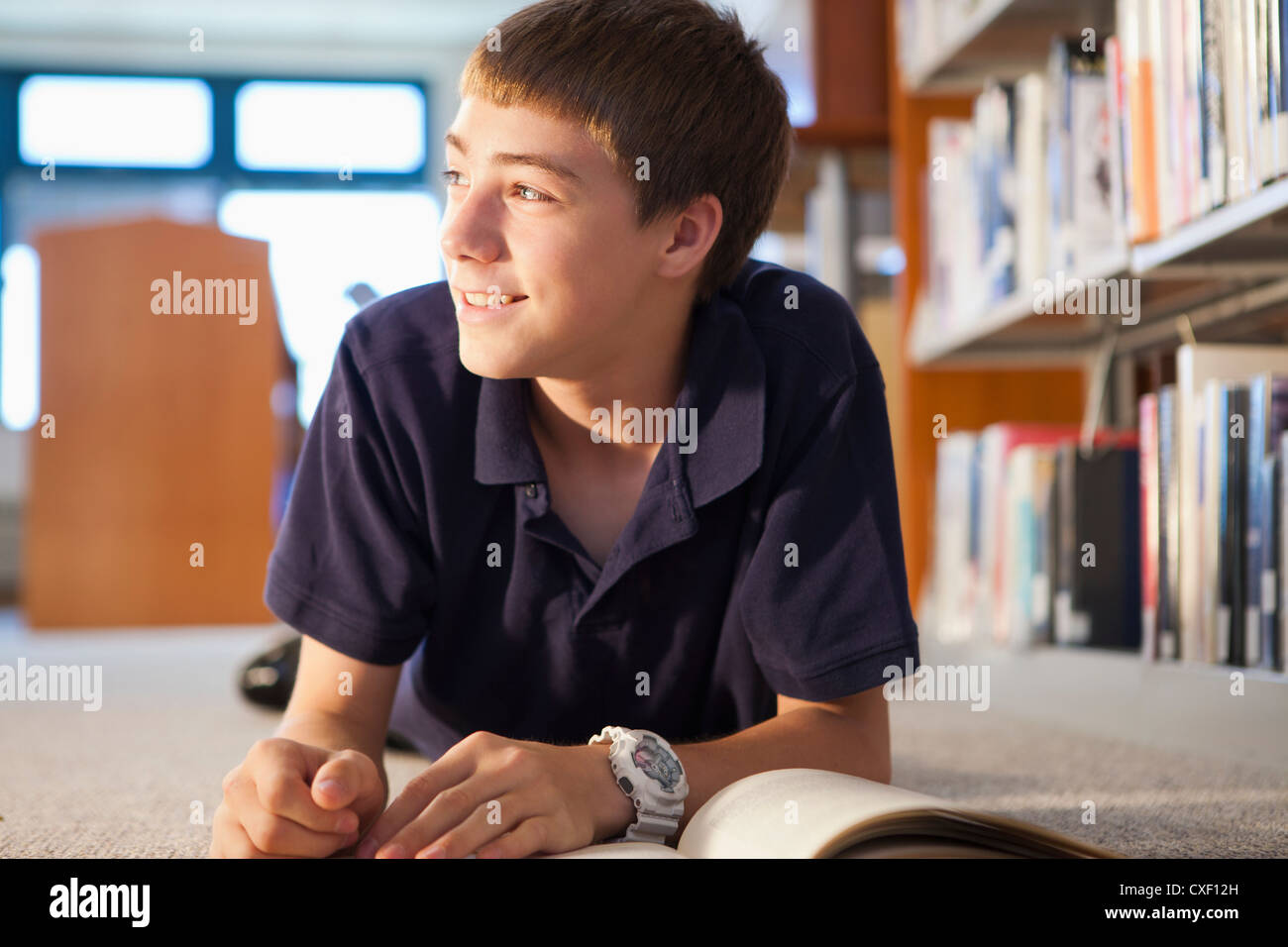 Caucasian boy reading book in library Stock Photo - Alamy
