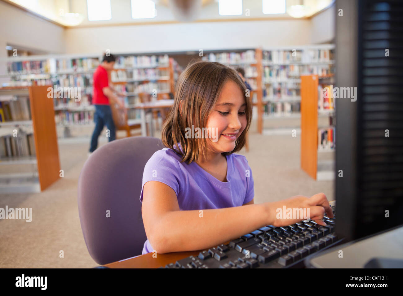 Girl using computer in library Stock Photo - Alamy