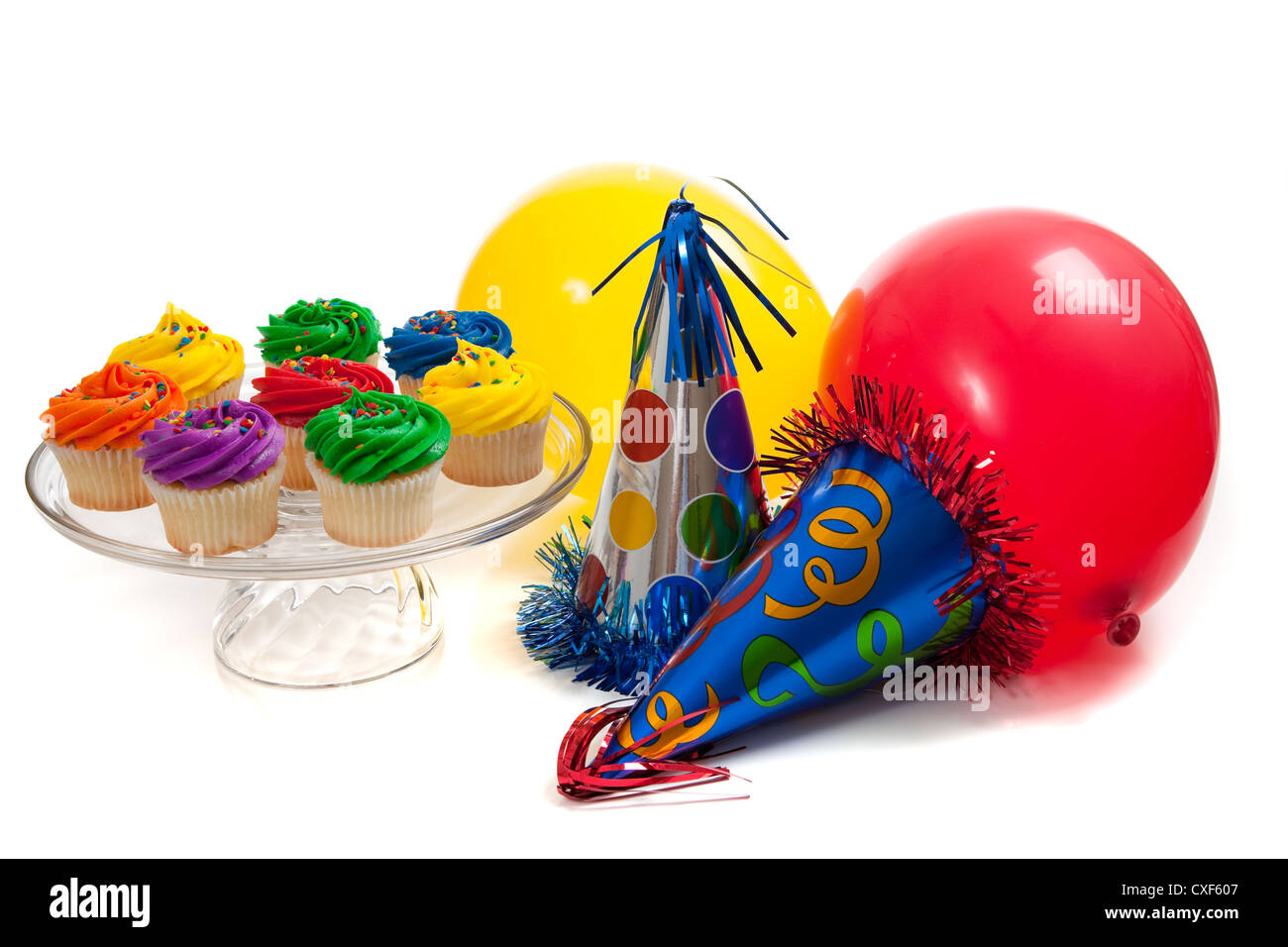 Brightly colored frosted cupcakes with birthday hats and balloons in ...