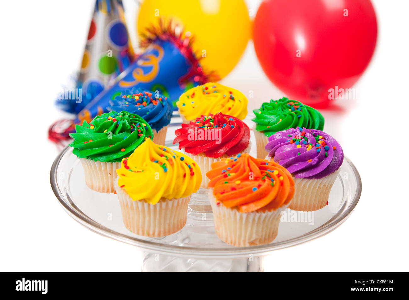 Brightly colored frosted cupcakes with birthday hats and balloons in ...