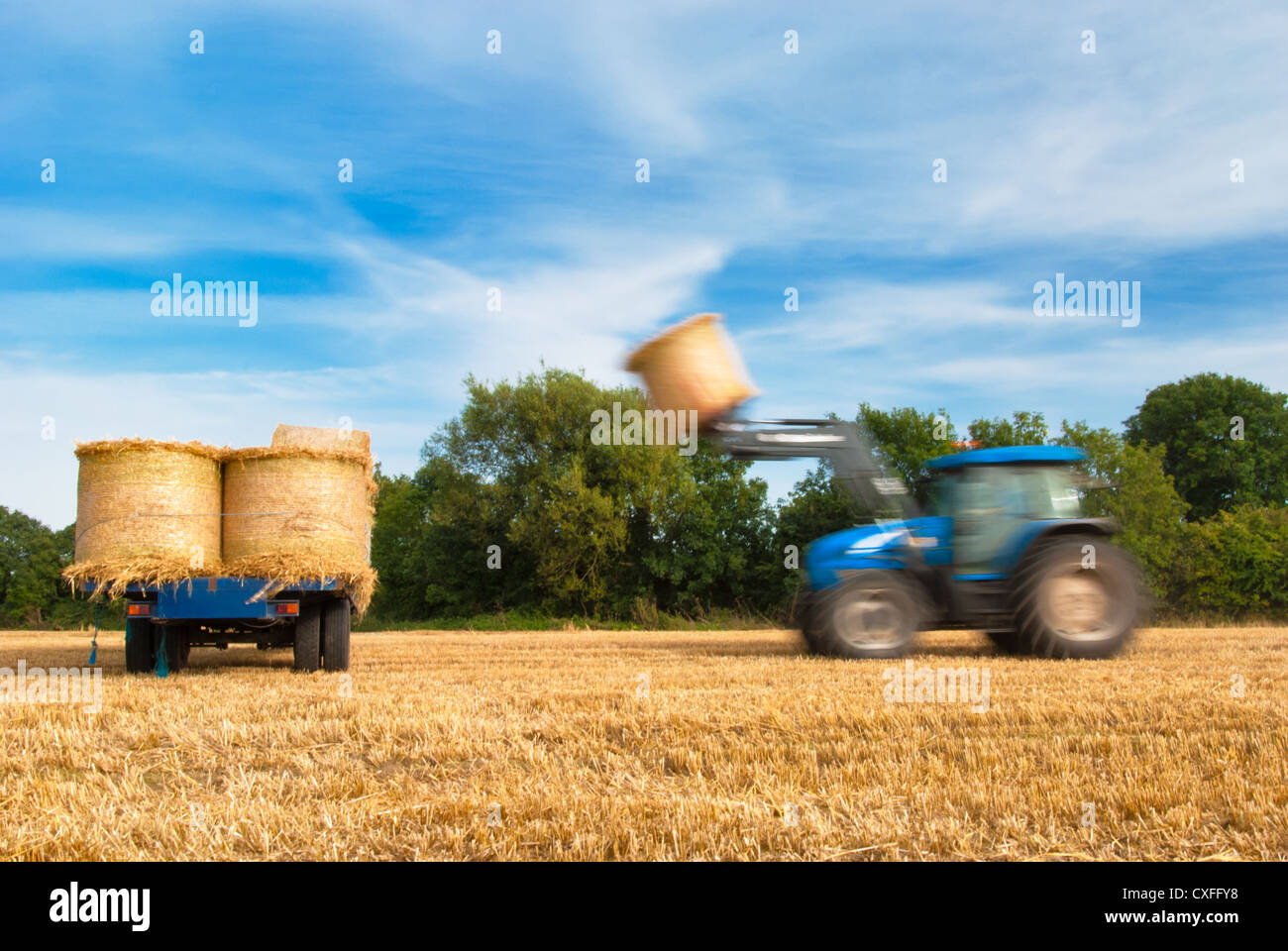 Make hay while the sun shines. A tractor works fast to collect the hay ...