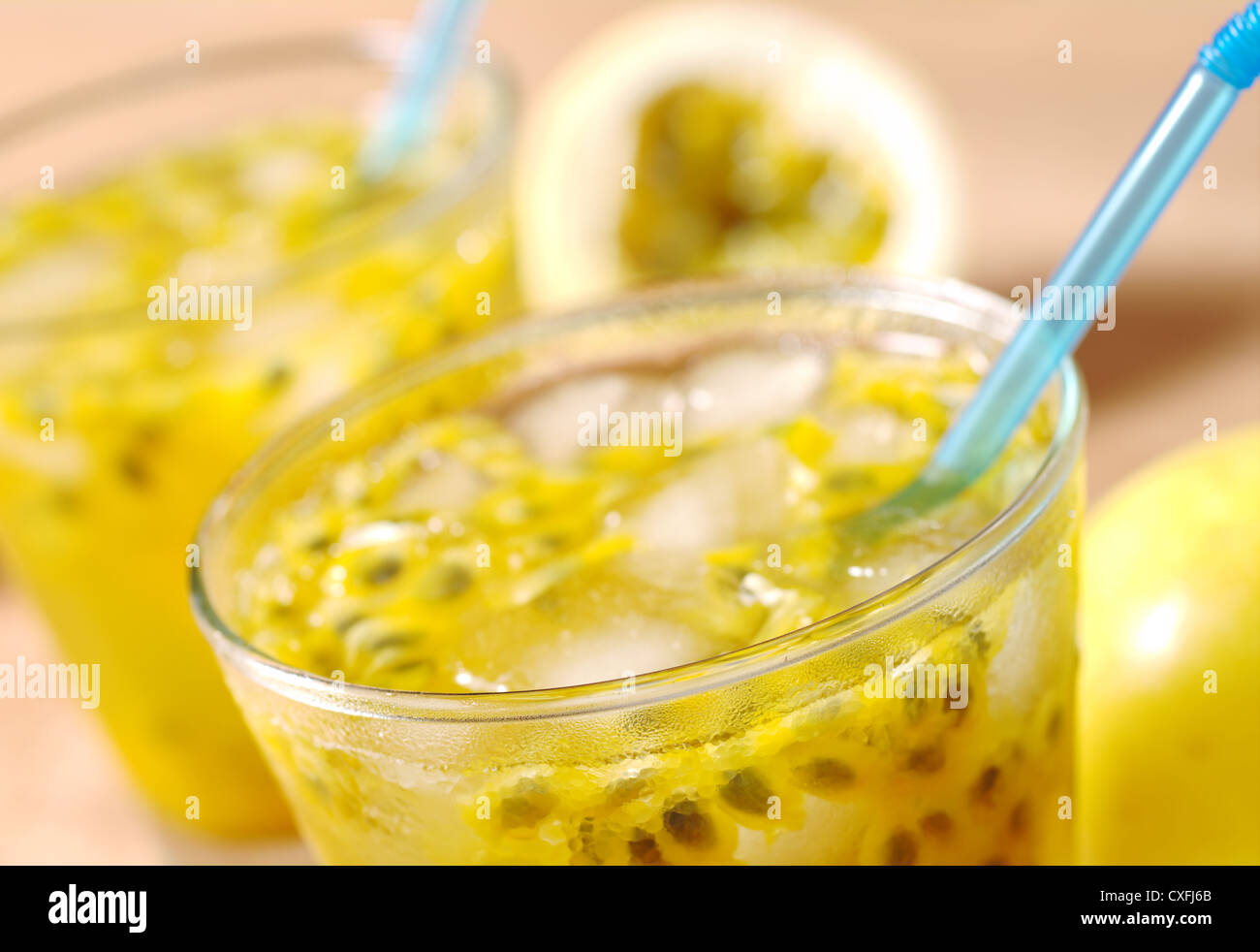 Passion fruit juice with ice cubes and blue drinking straws with ...