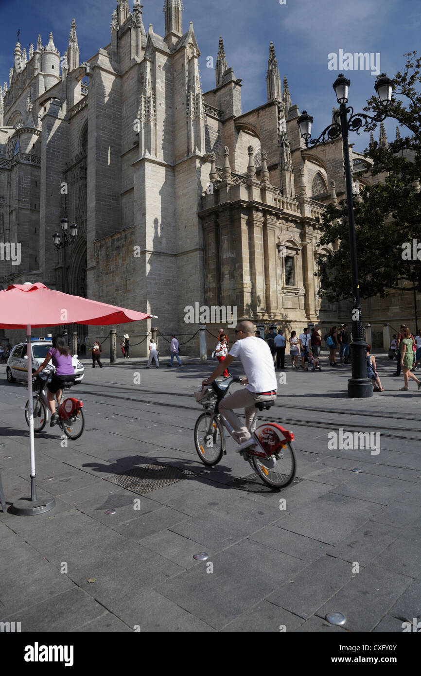 Man and woman riding Sevici community rental bikes in the Plaza Virgen ...