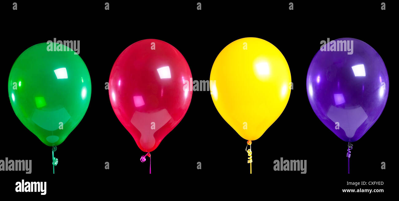 A group of primary colored party balloons on a black background with ...