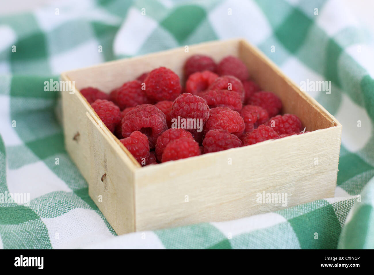 A small wooden box filled with raspberries Stock Photo - Alamy