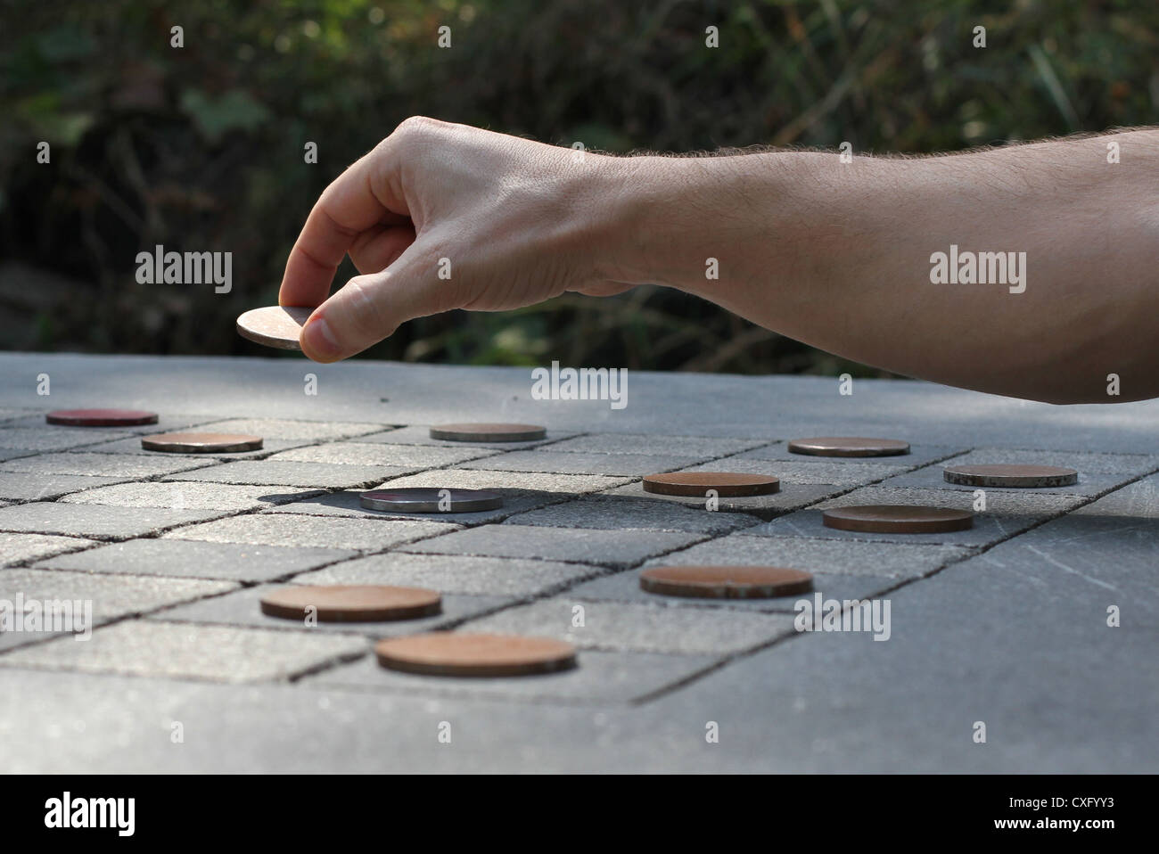 A hand moving a checker piece on a large outdoor checker board Stock ...