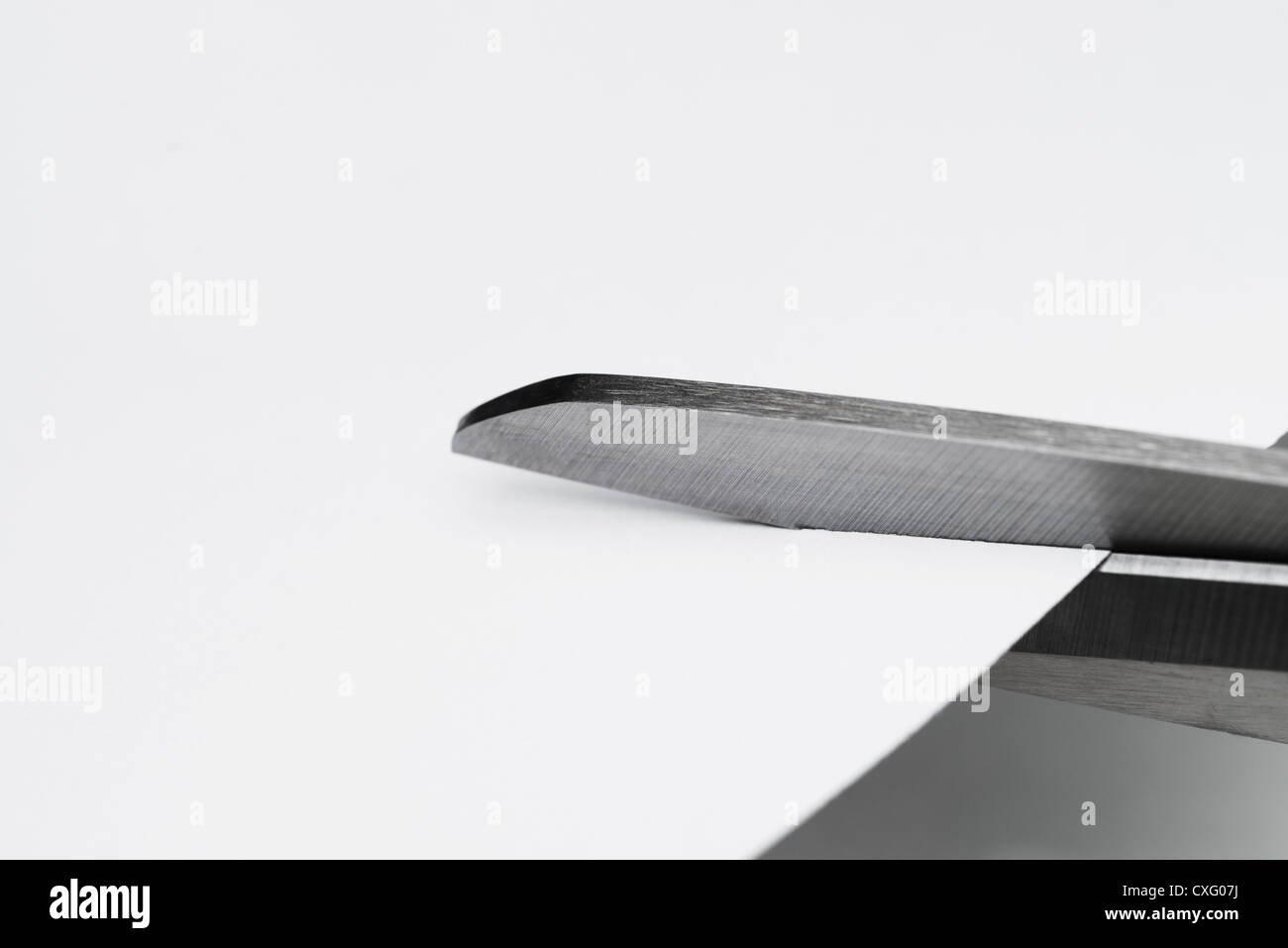 A pair of scissors cutting snipping a piece of paper Stock Photo - Alamy