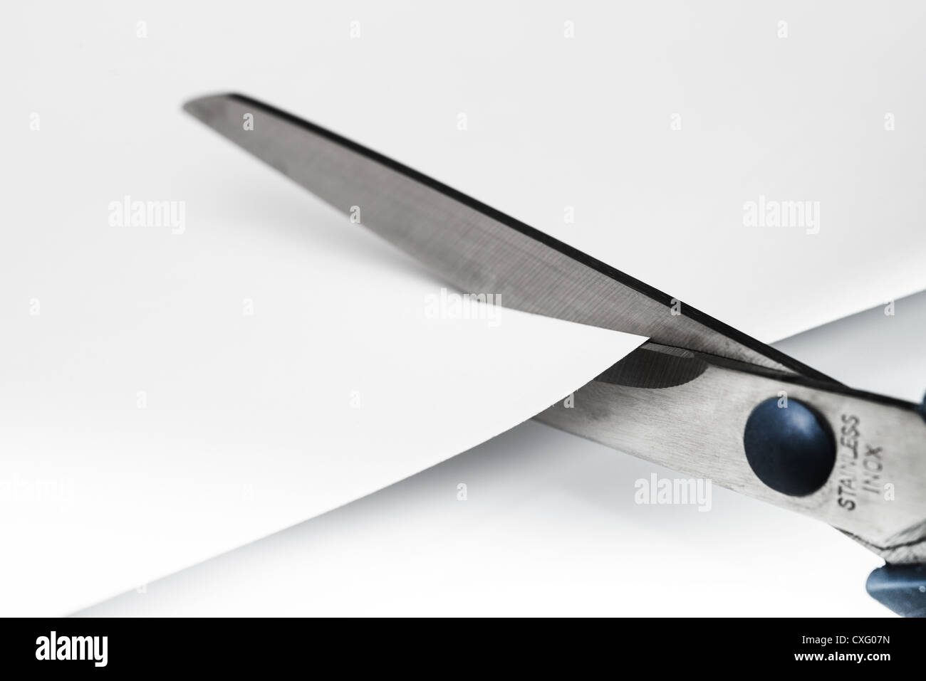 A pair of scissors cutting snipping a piece of paper Stock Photo - Alamy