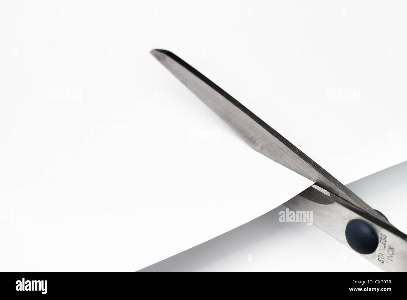 A pair of scissors cutting snipping a piece of paper Stock Photo - Alamy