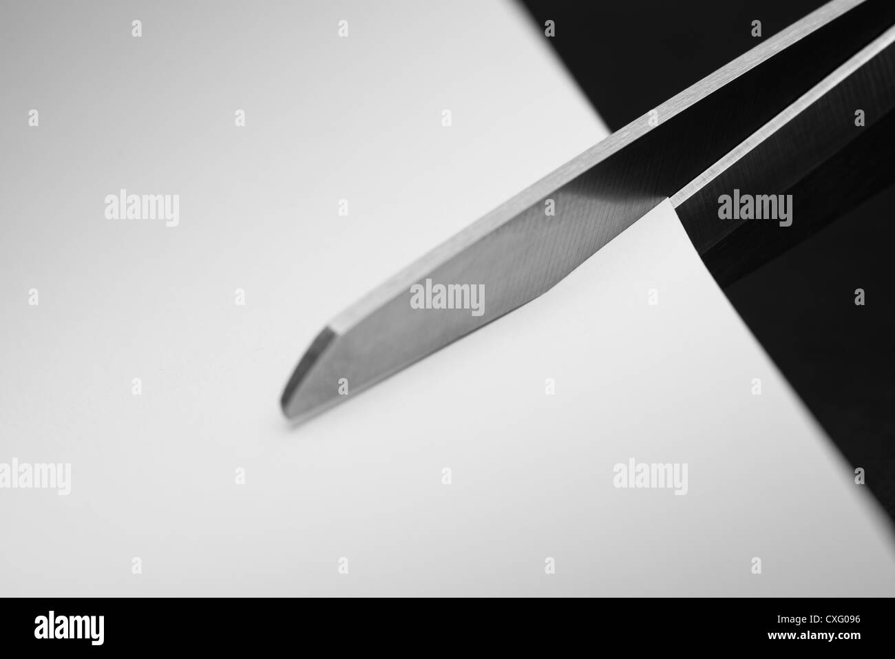 A pair of scissors cutting snipping a piece of paper Stock Photo - Alamy