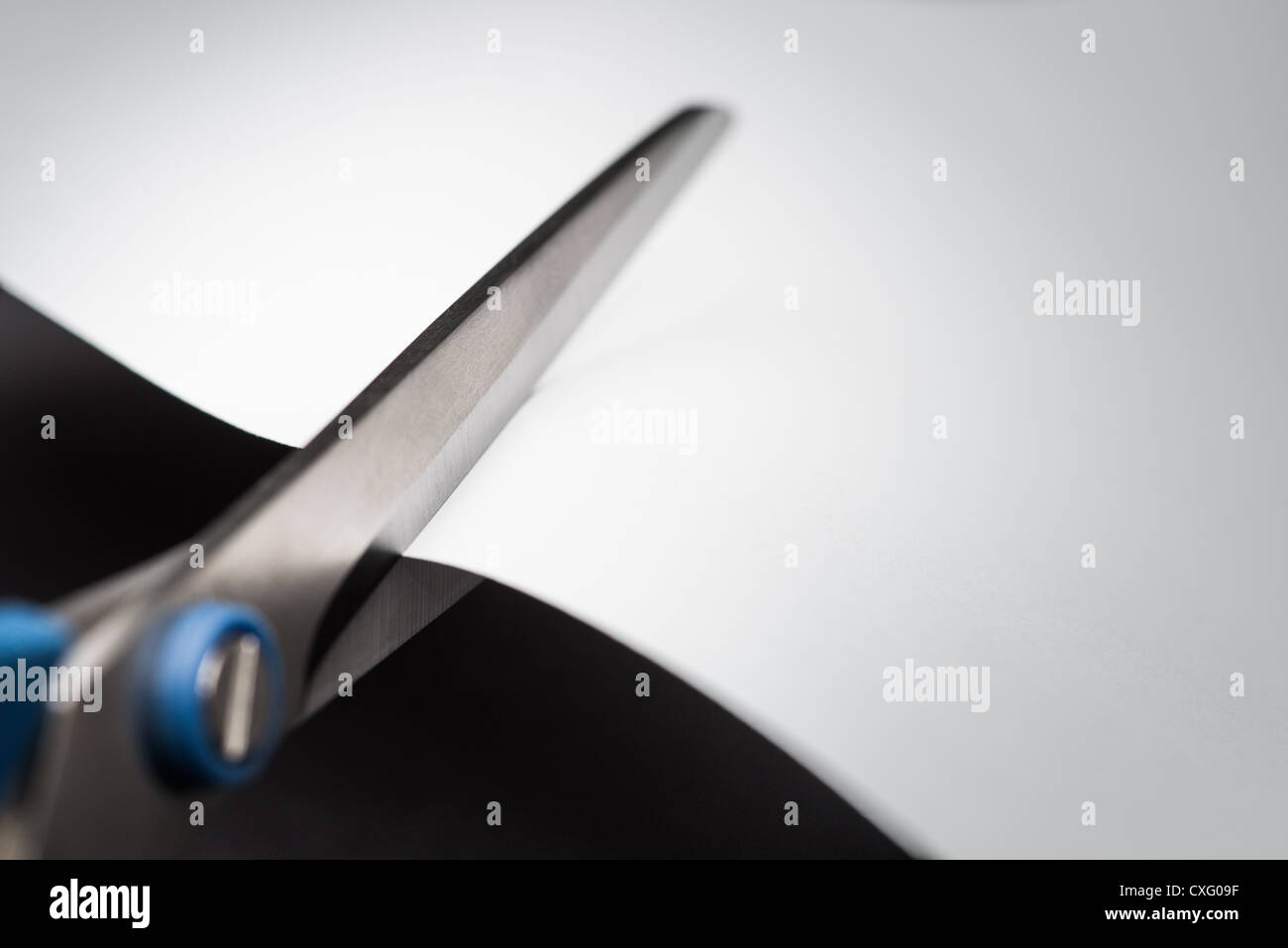 A pair of scissors cutting snipping a piece of paper Stock Photo - Alamy