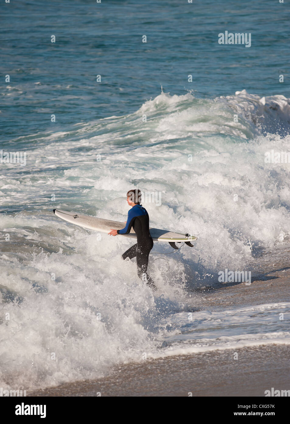 A surfer running into the surf at Sennen in Cornwall Stock Photo - Alamy