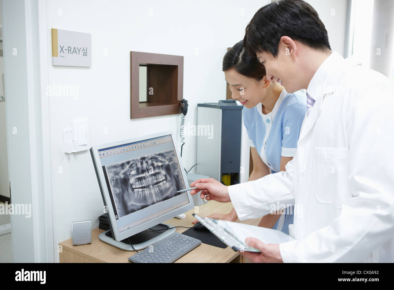A dentist and a nurse looking at a teeth x-ray in a computer Stock ...