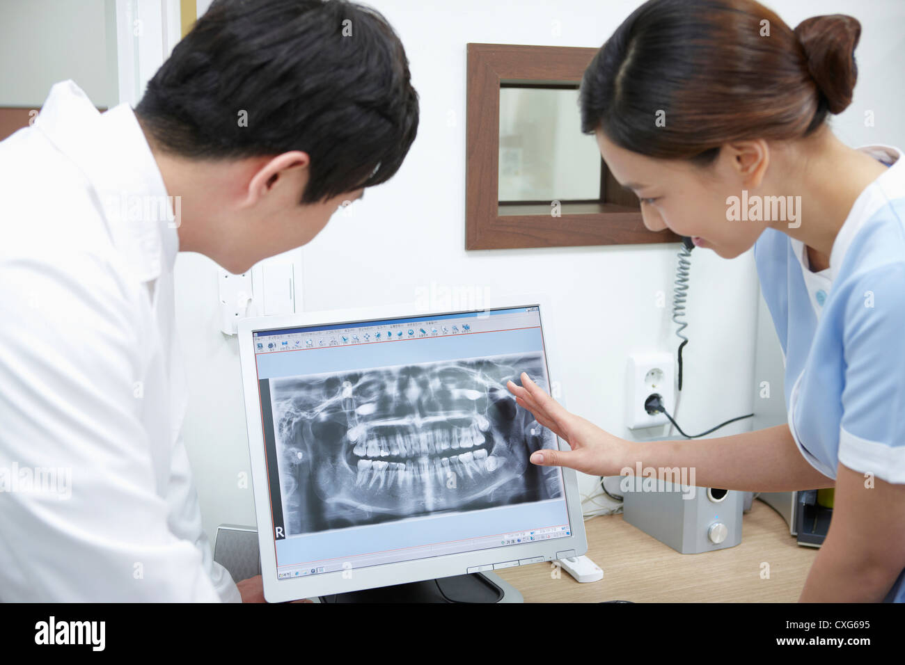 A dentist and a nurse watching teeth x-ray picture in a computer Stock ...
