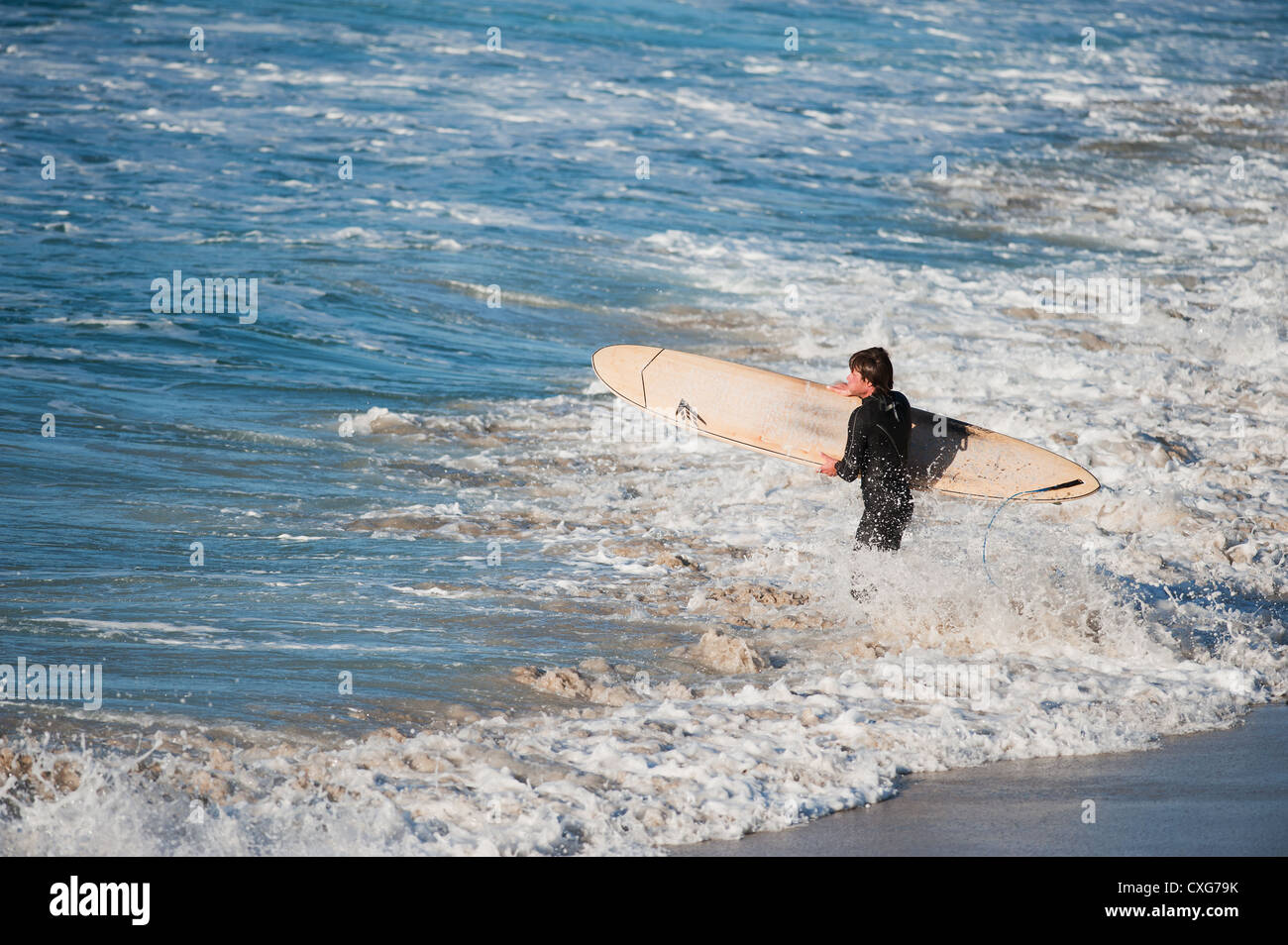 A surfer running into the surf at Sennen in Cornwall Stock Photo - Alamy