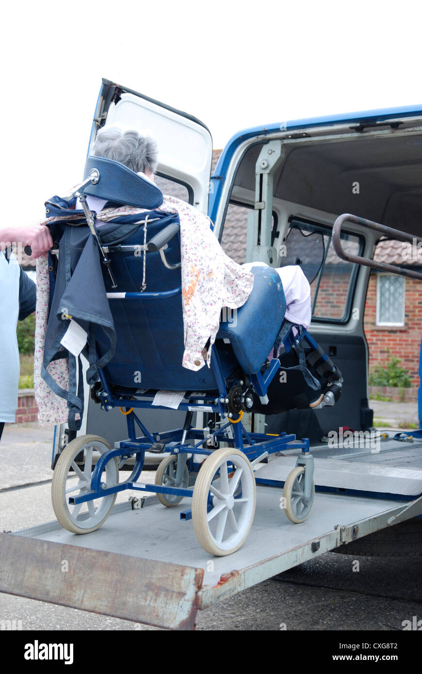 Elderly woman in a wheelchair on platform ramp lift of a specialised ...