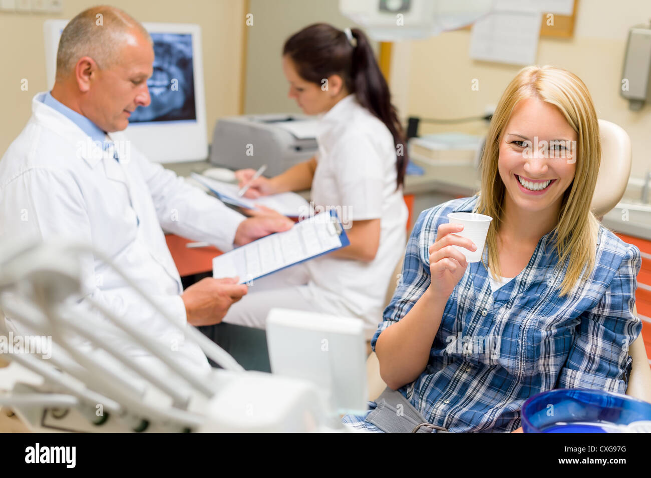 Woman beautiful smile at dental surgery male dentist check documents ...