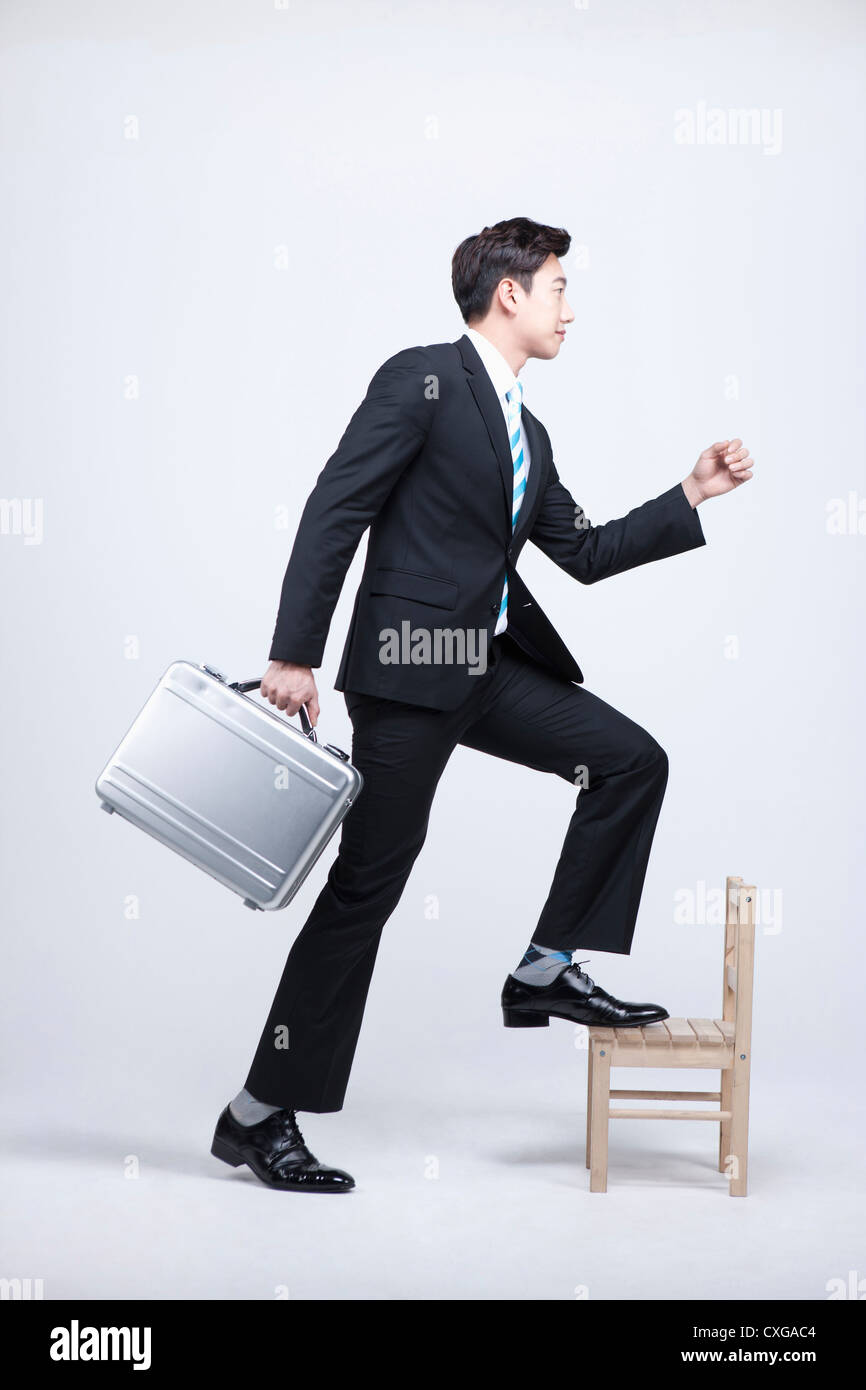 man carrying a briefcase and stepping up the wooden chair Stock Photo ...