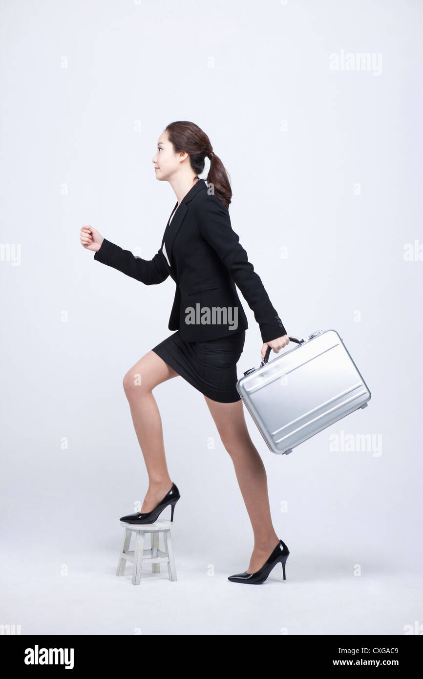woman carrying a briefcase and stepping up the wooden chair Stock Photo ...