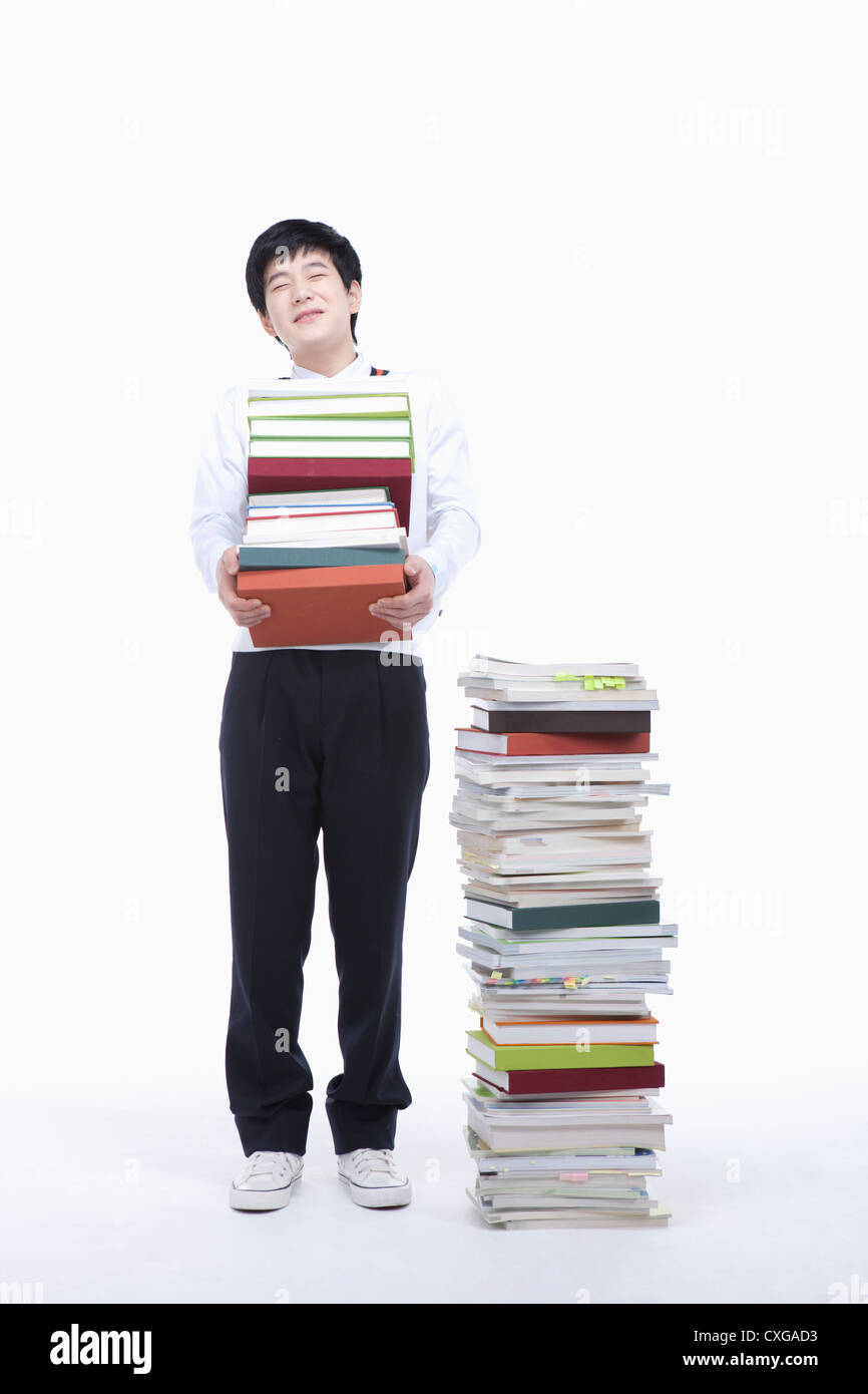 schoolboy holding books next to a stack of books Stock Photo - Alamy