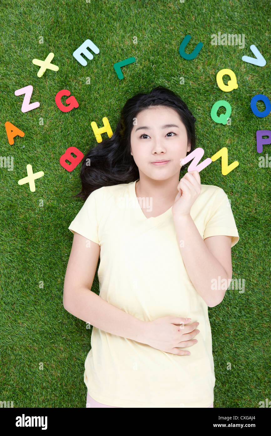 girl lying on the ground and holding a letter of N Stock Photo - Alamy