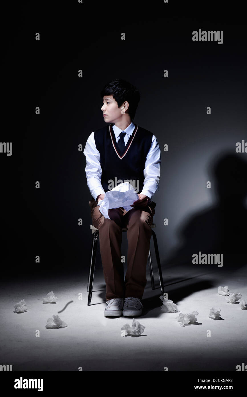 schoolboy sitting on the chair in a dark room Stock Photo - Alamy