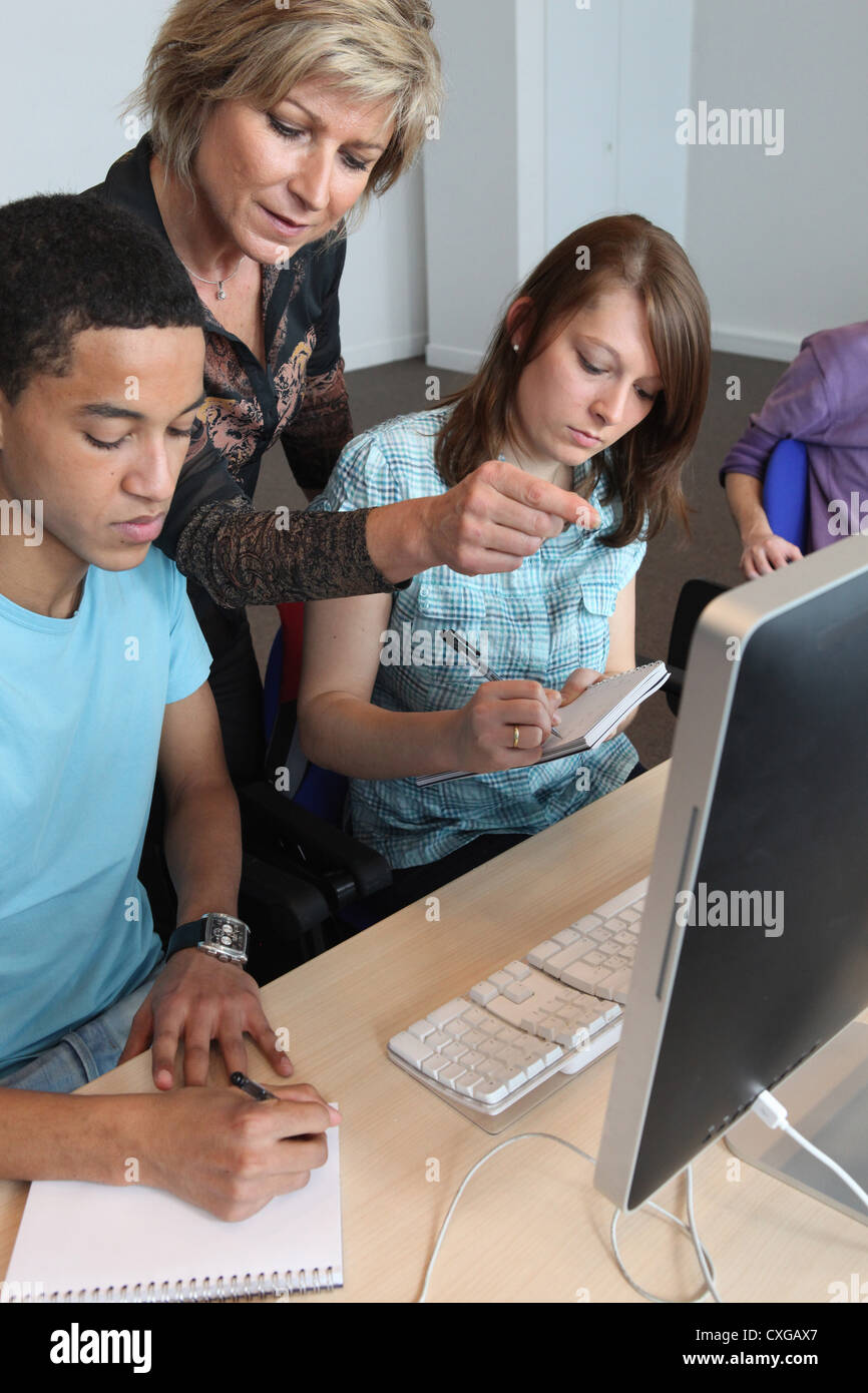 Teacher helping pupils with their assignment Stock Photo - Alamy