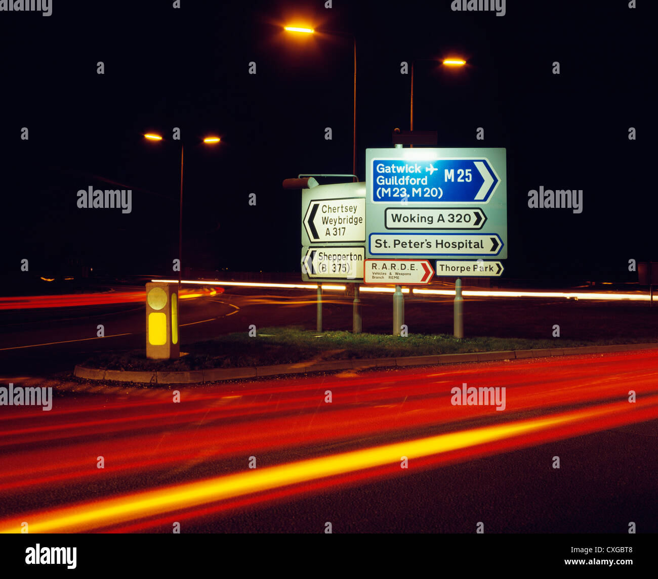 Road signs on roundabout above the M25 at Chertsey, Surrey, England ...