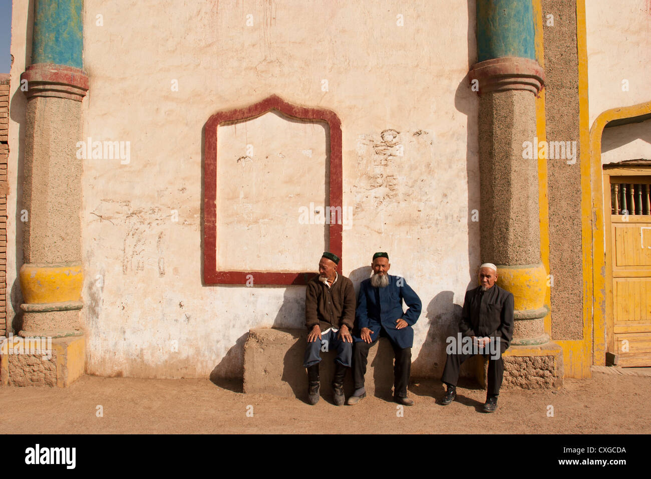 Uighur men sit outside a mosque in a village at the foot of the Flaming ...