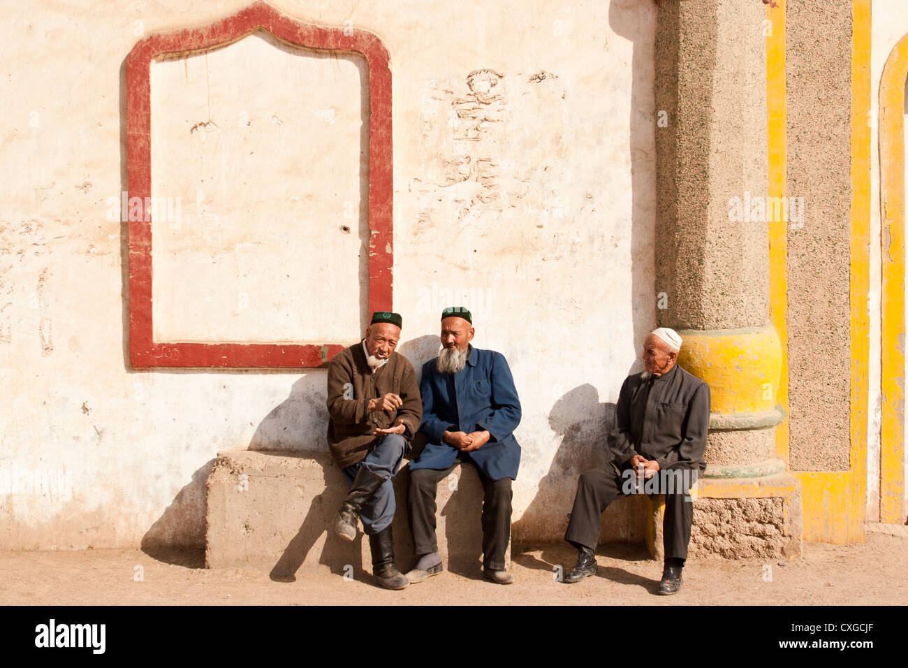 Uighur men sit outside a mosque in a village at the foot of the Flaming ...
