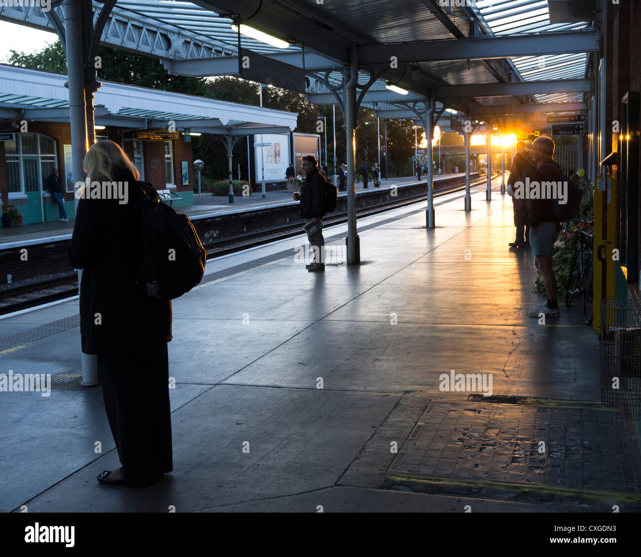 Commuters wait for a train in the early morning sun Stock Photo - Alamy