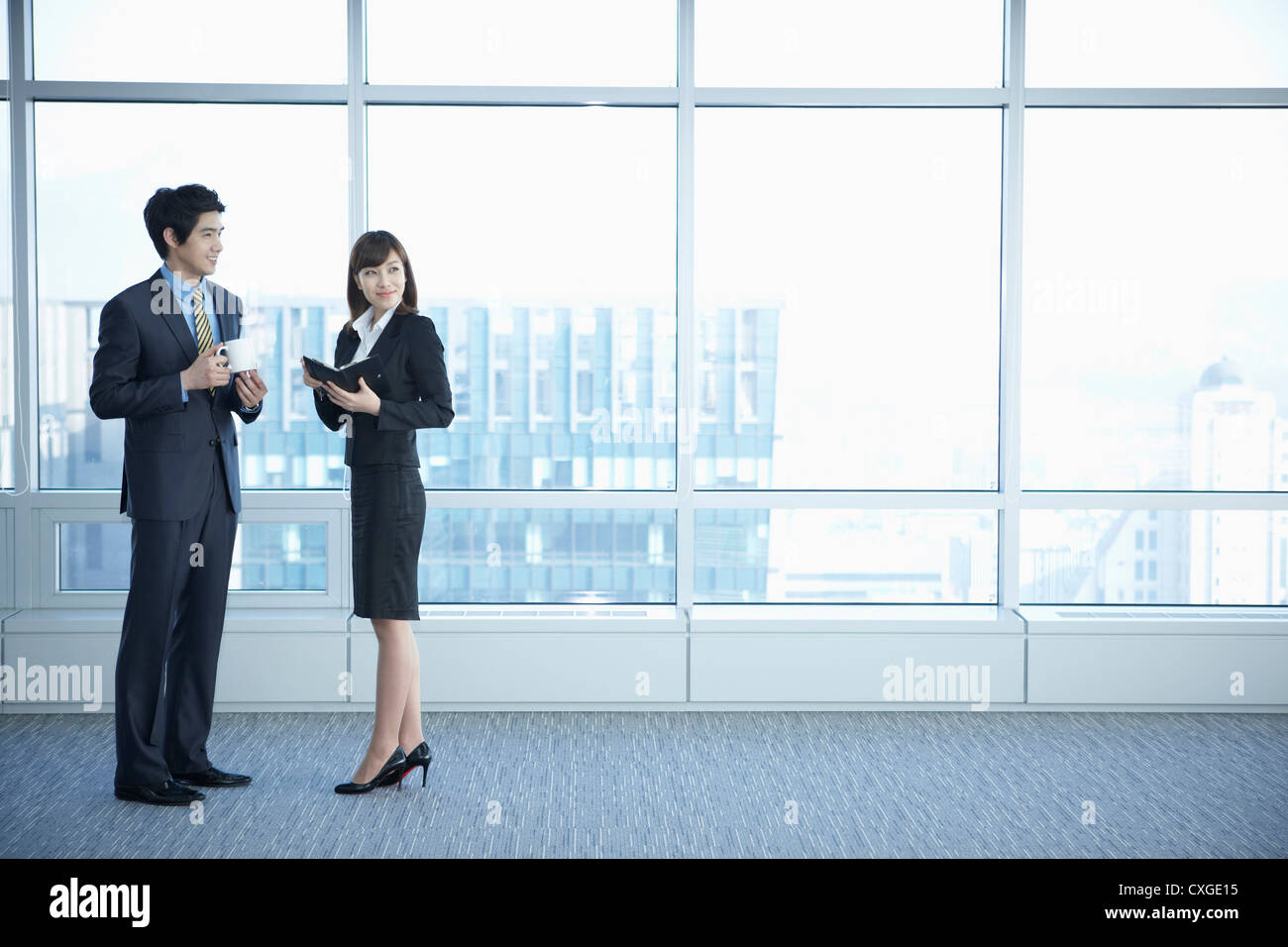 A business woman and a man standing next to long wide windows Stock ...