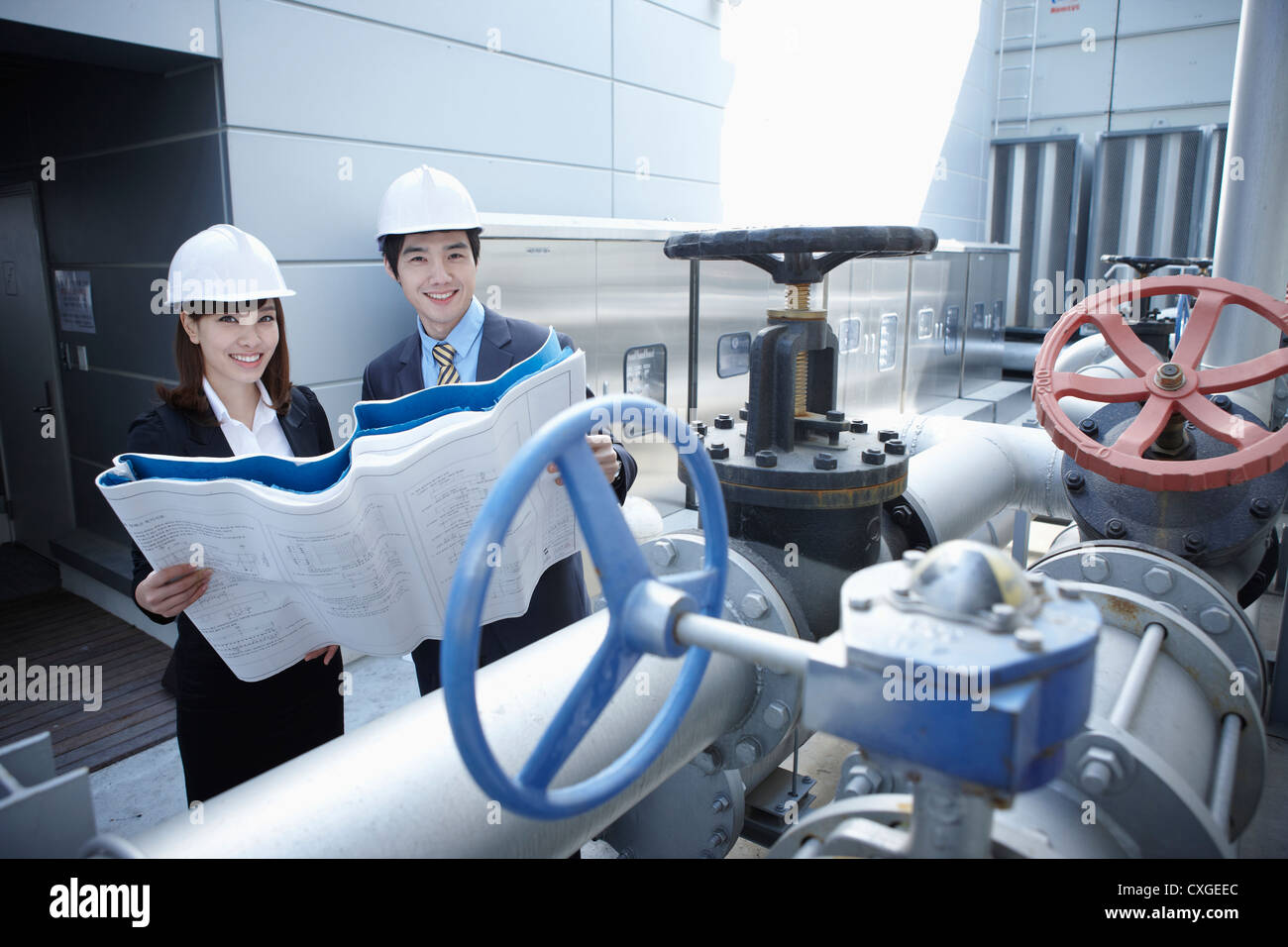 Architects smiling while looking at a pipeline valve Stock Photo - Alamy