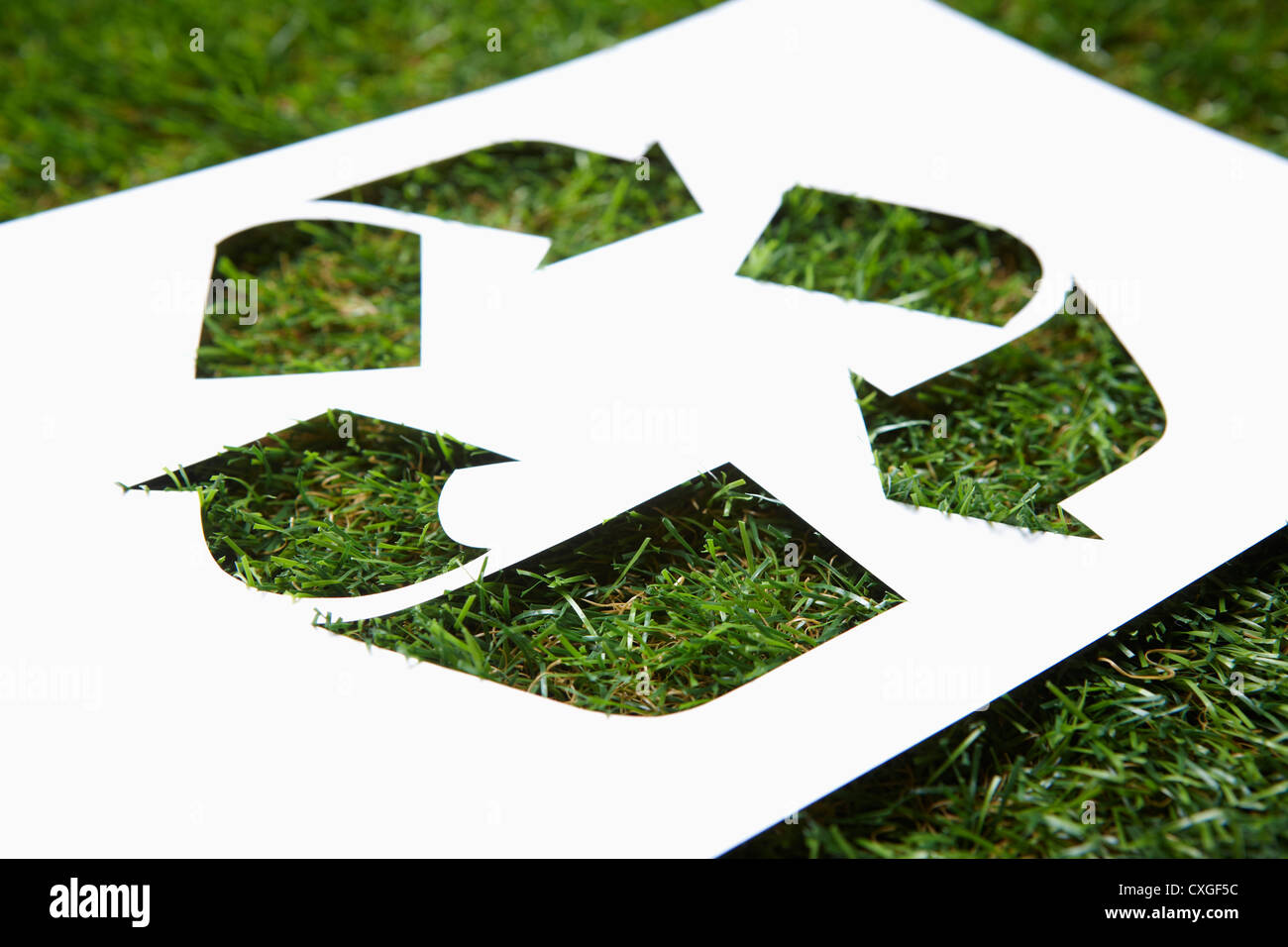 Recycling logo cut into a paper and placed on grass Stock Photo - Alamy