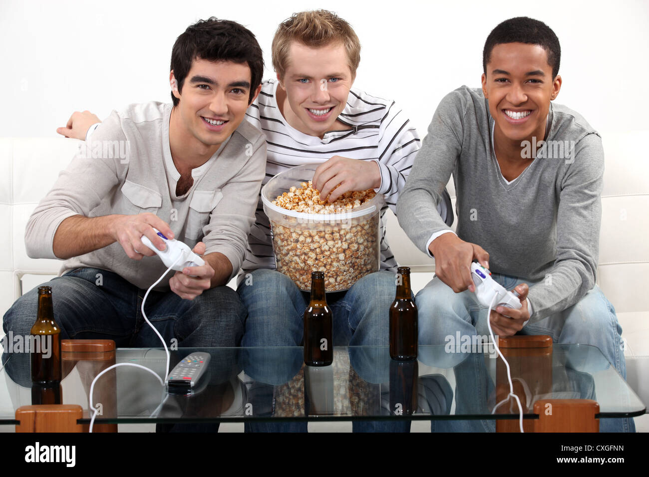 Three friends playing video games while drinking beer Stock Photo - Alamy