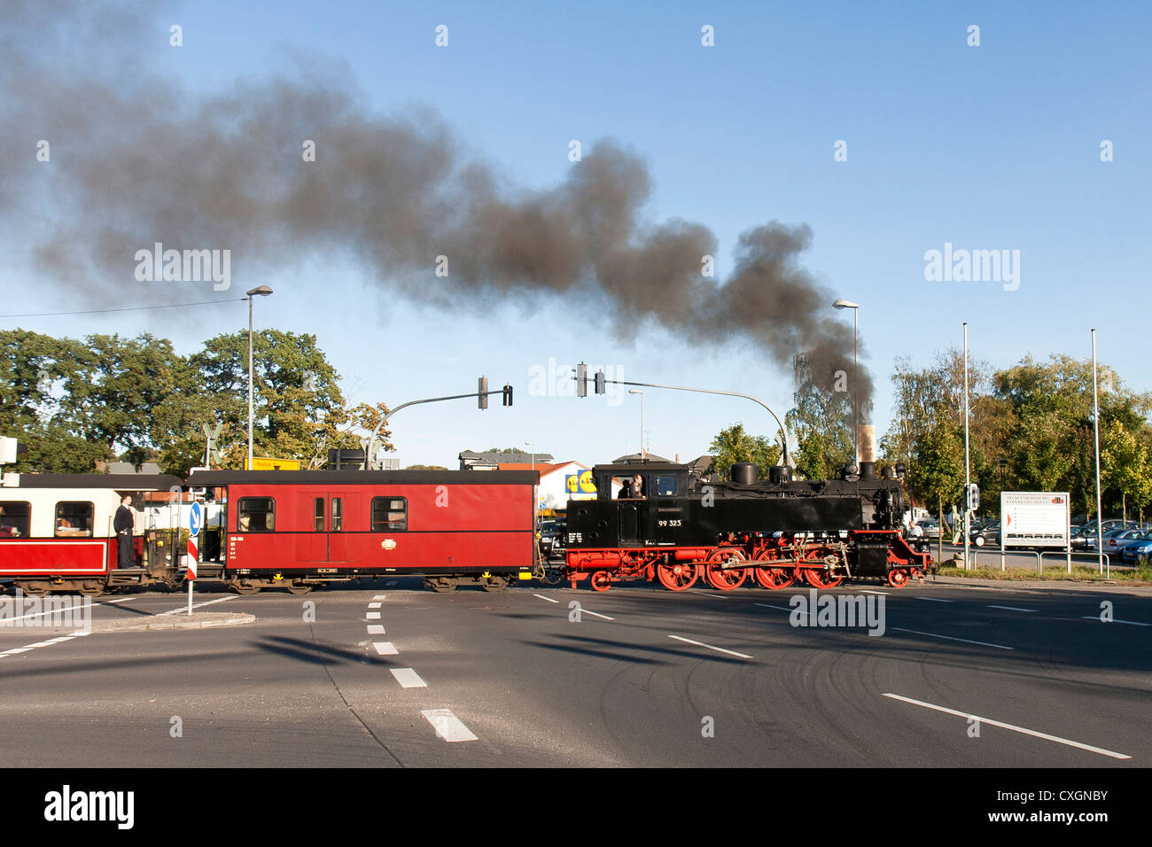 Steam locomotive pulling a passenger train across the road. The Molli ...