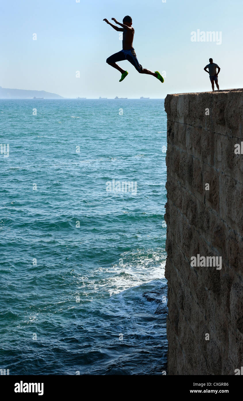Teens, jumping into the sea from a height of city walls of Acre Stock ...