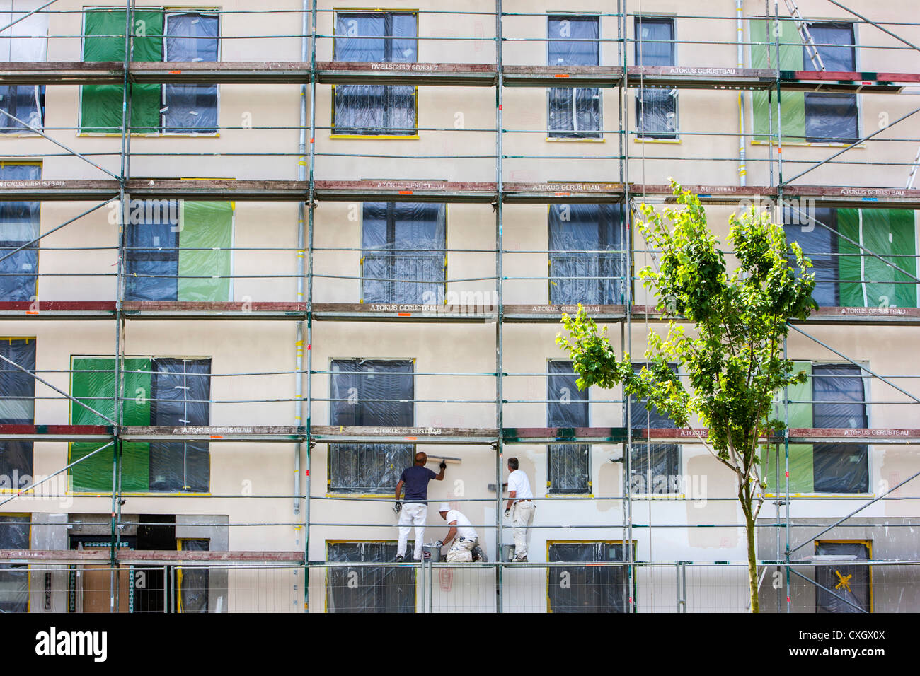 Worker on a scaffolding, plastering the wall of a new apartment ...