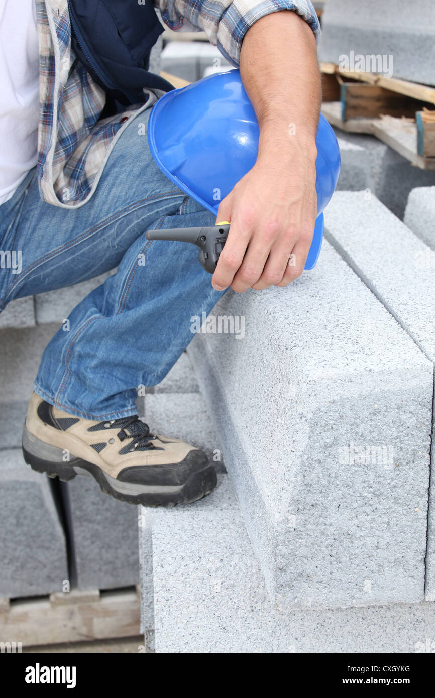 Construction worker kneeling by concrete blocks Stock Photo - Alamy