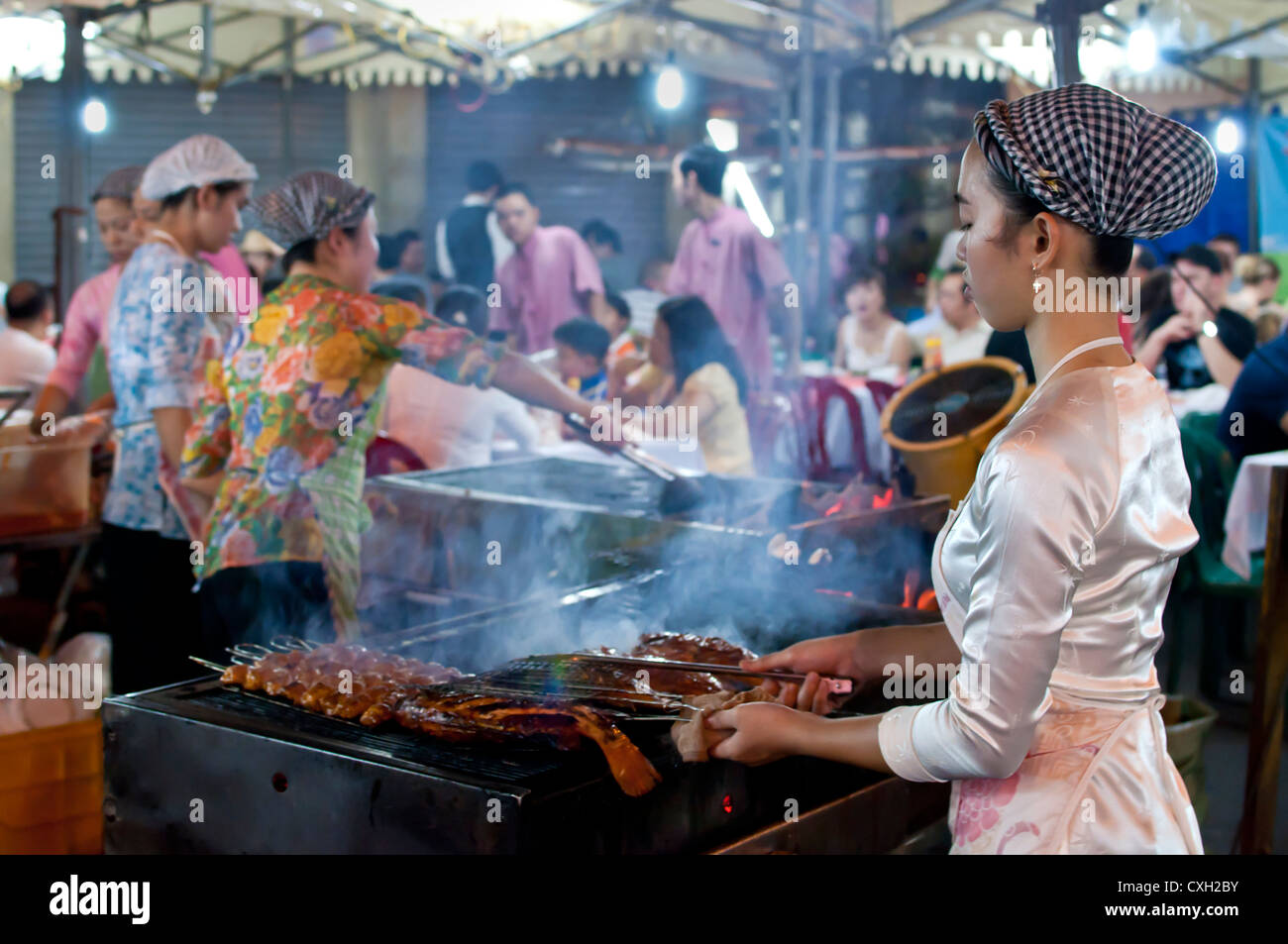 Girl grilling seafood at a restaurant at Ben Thanh night market, Ho Chi ...