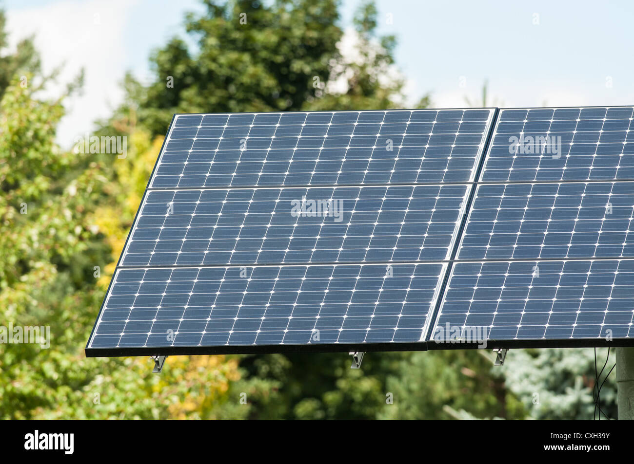 A photovoltaic solar panel stands in front of green trees Stock Photo ...