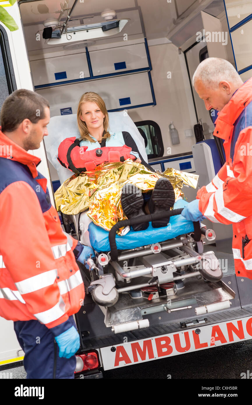 Paramedics with injured woman on stretcher in ambulance helping ...