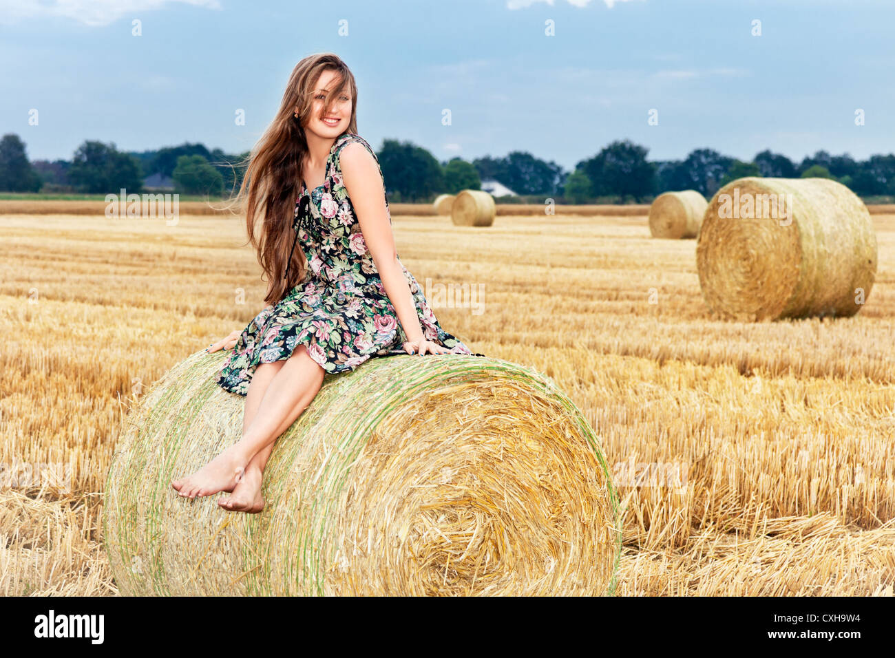 Woman sitting on hay bale Stock Photo - Alamy