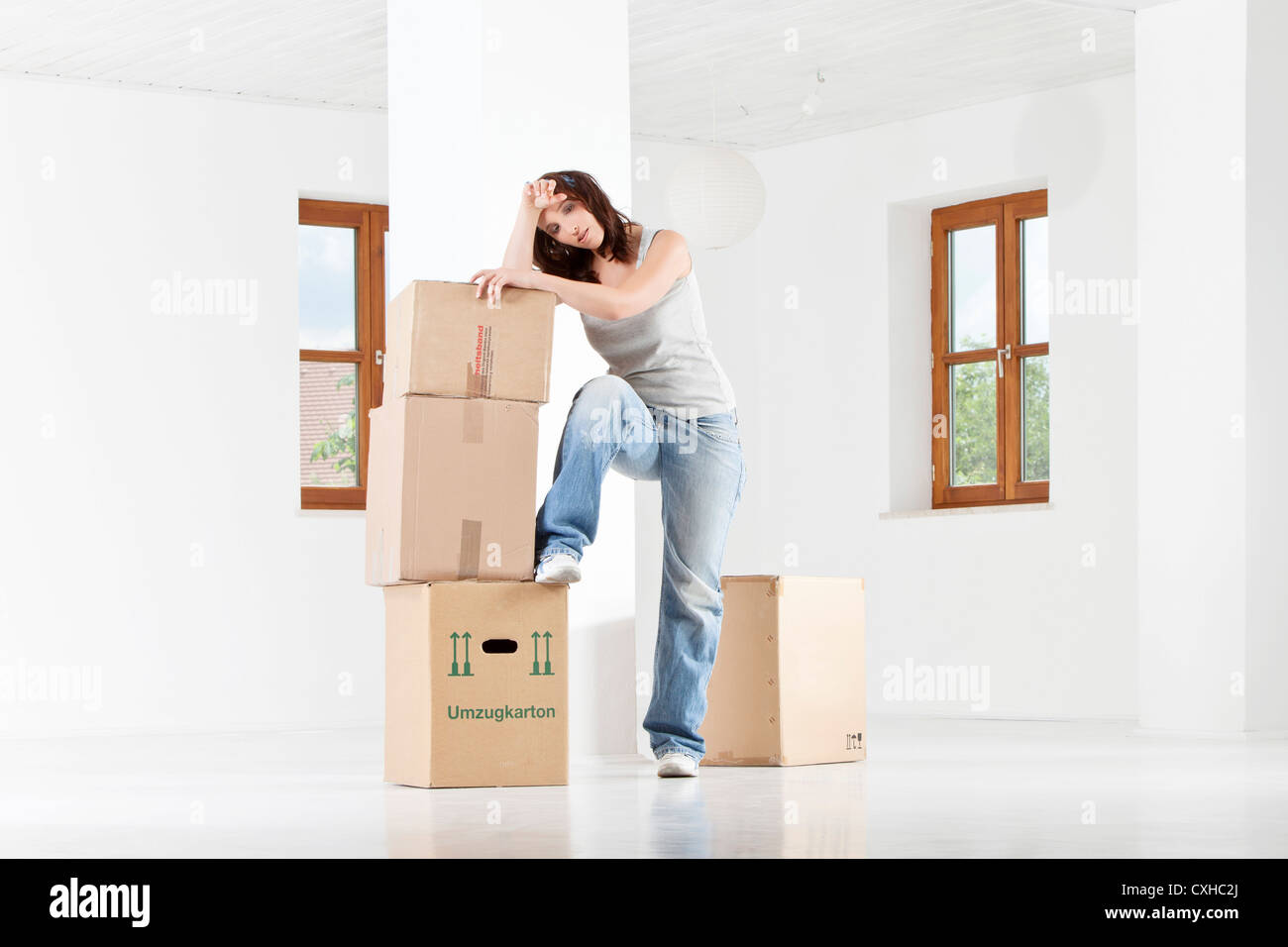 Young woman leaning on cardboard boxes Stock Photo - Alamy