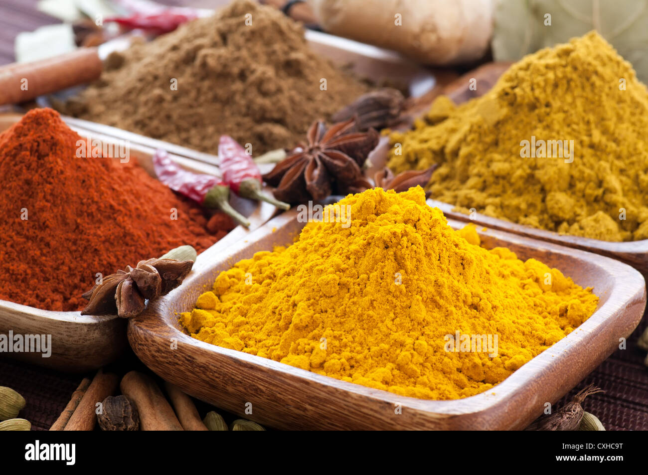 Exotically colorful spice mix with different podwer and grain in teak ...