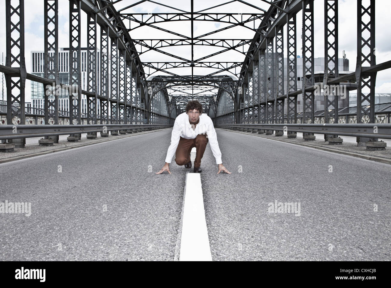 Germany, Bavaria, Young businessman in starting position on bridge ...