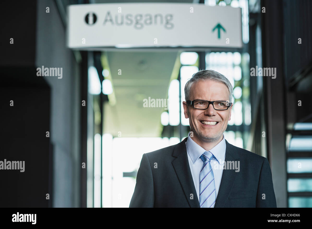 Germany, Stuttgart, Businessman standing in office building, smiling ...