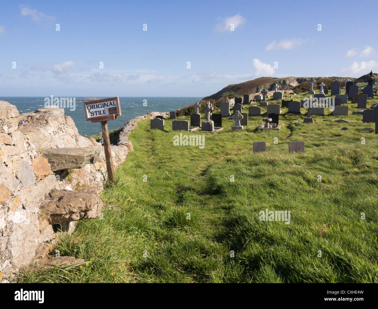 Original old stone stile with sign on churchyard wall around St Patrick ...