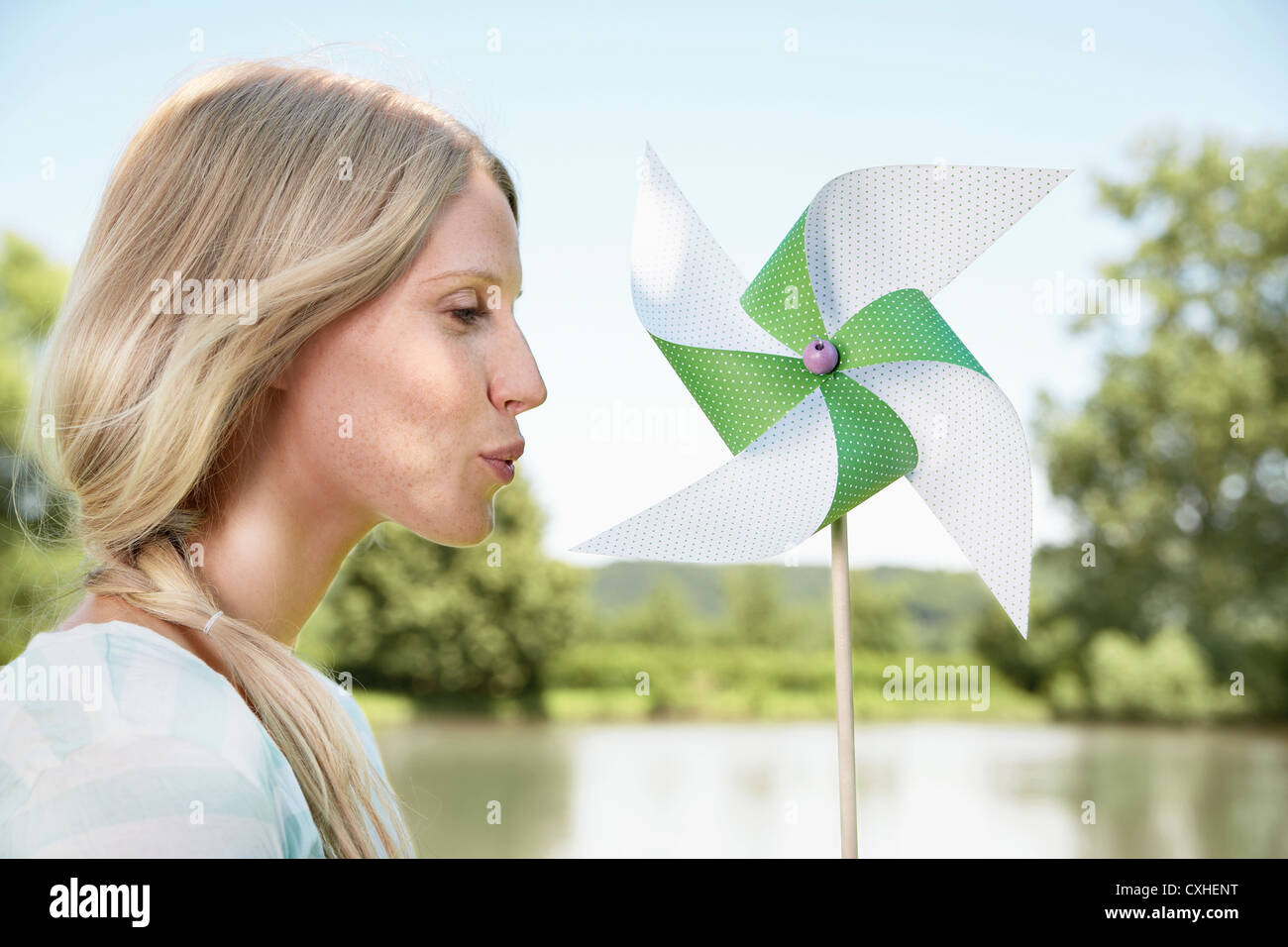 Germany, Cologne, Young woman blowing paper windmill Stock Photo - Alamy